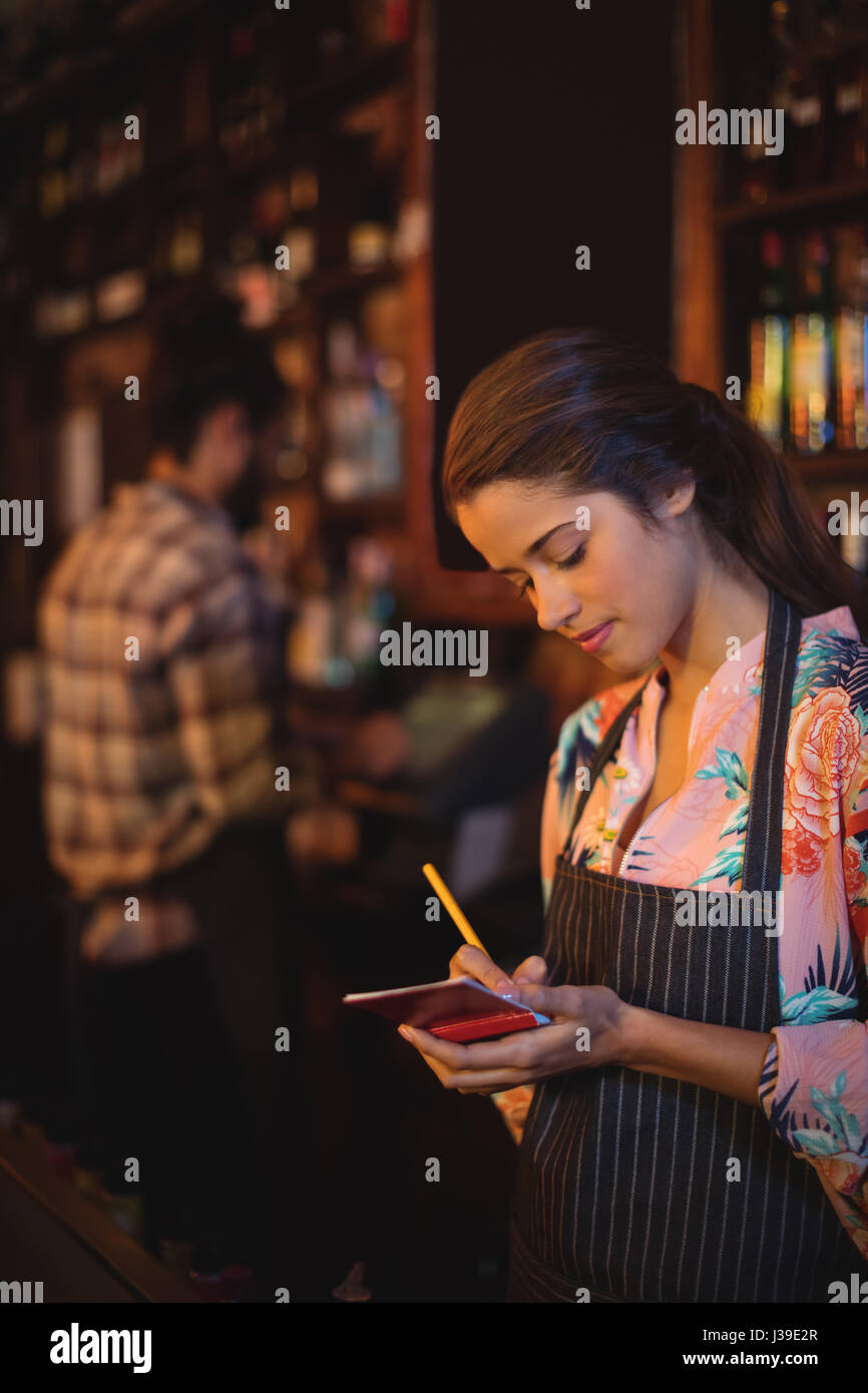 Waitress taking an order on notepad at counter in pub Stock Photo - Alamy