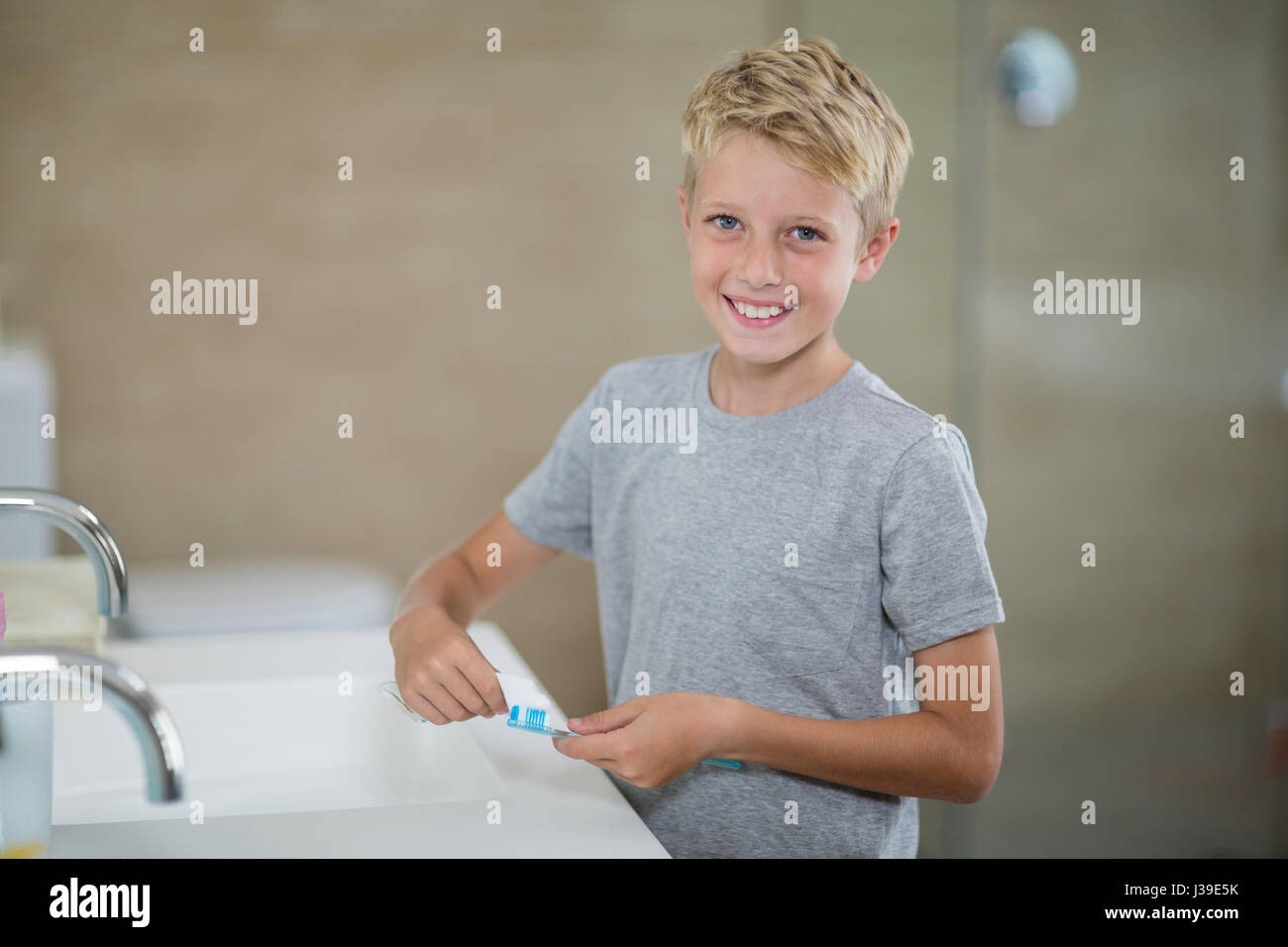 Portrait of boy putting toothpaste on brush in bathroom at home Stock ...