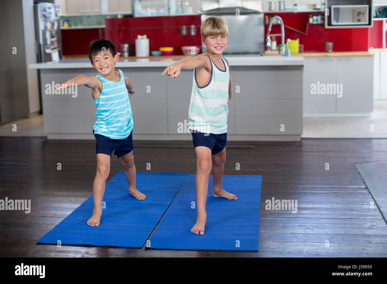 Portrait of smiling siblings doing stretching exercise in kitchen Stock ...