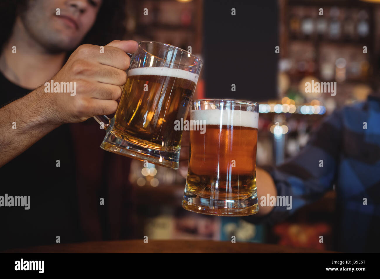 Two young men toasting their beer mugs in pub Stock Photo - Alamy