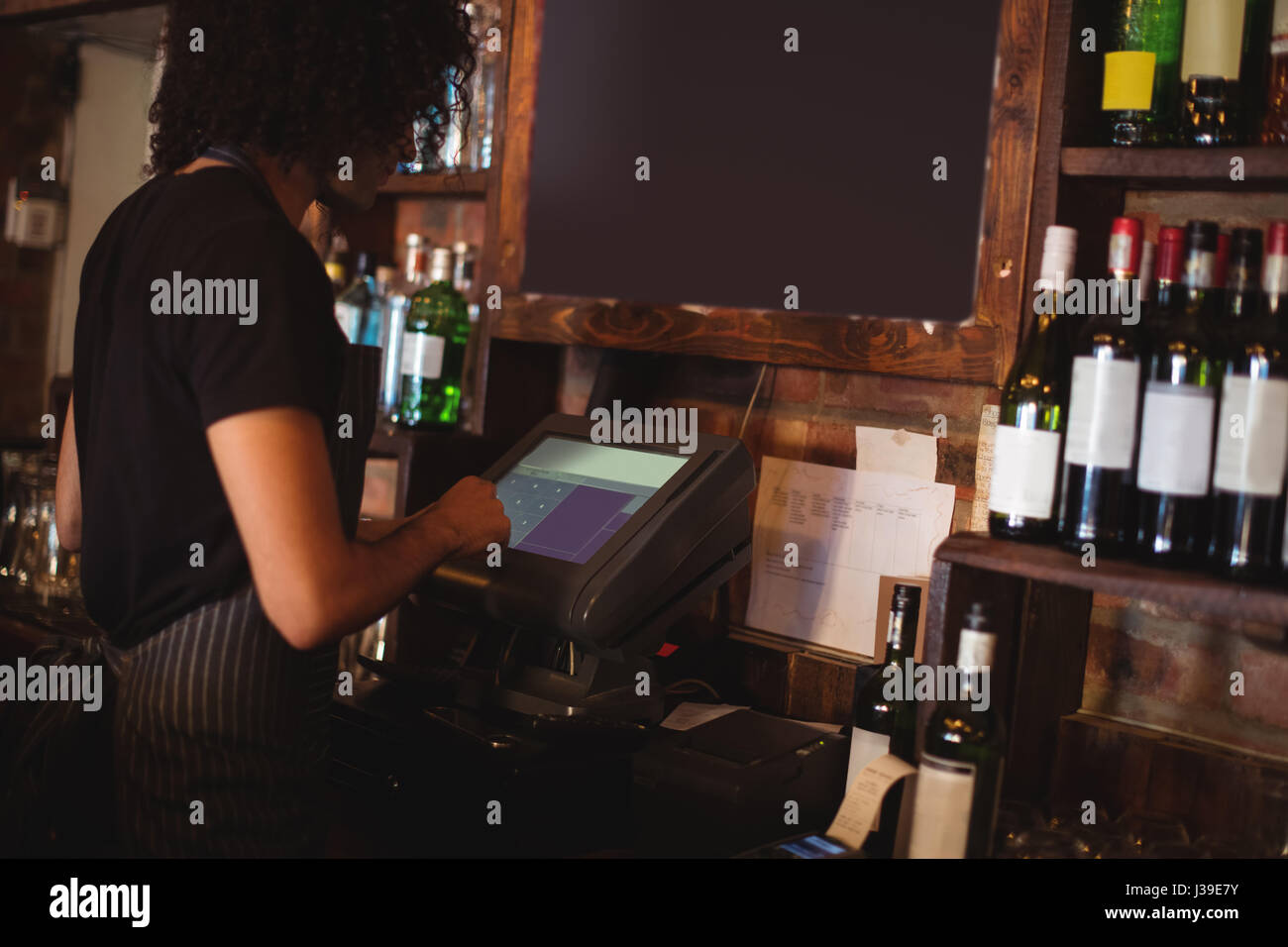 Young waiter using a machine in pub Stock Photo - Alamy