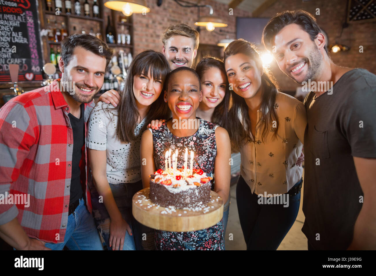 Portrait of happy friends holding birthday cake in restaurant Stock ...