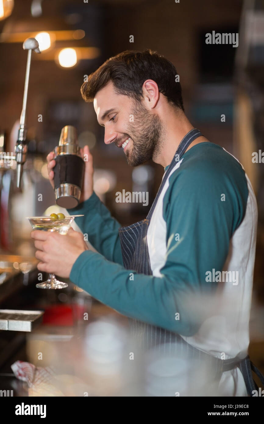 Side view of smiling bartender making drinks in bar Stock Photo - Alamy