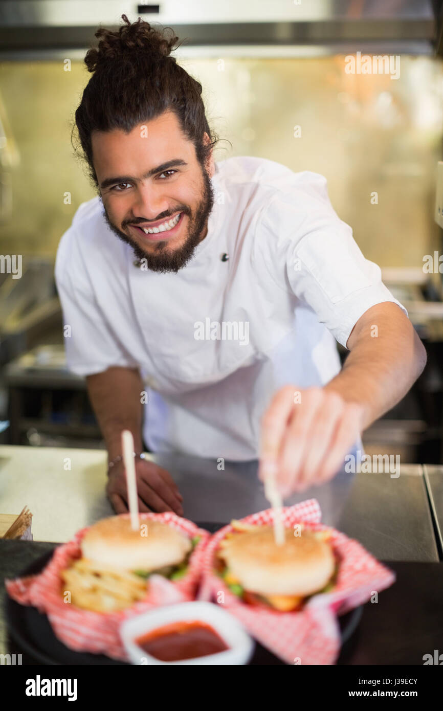Portrait of happy male chef preparing burger in commercial kitchen ...