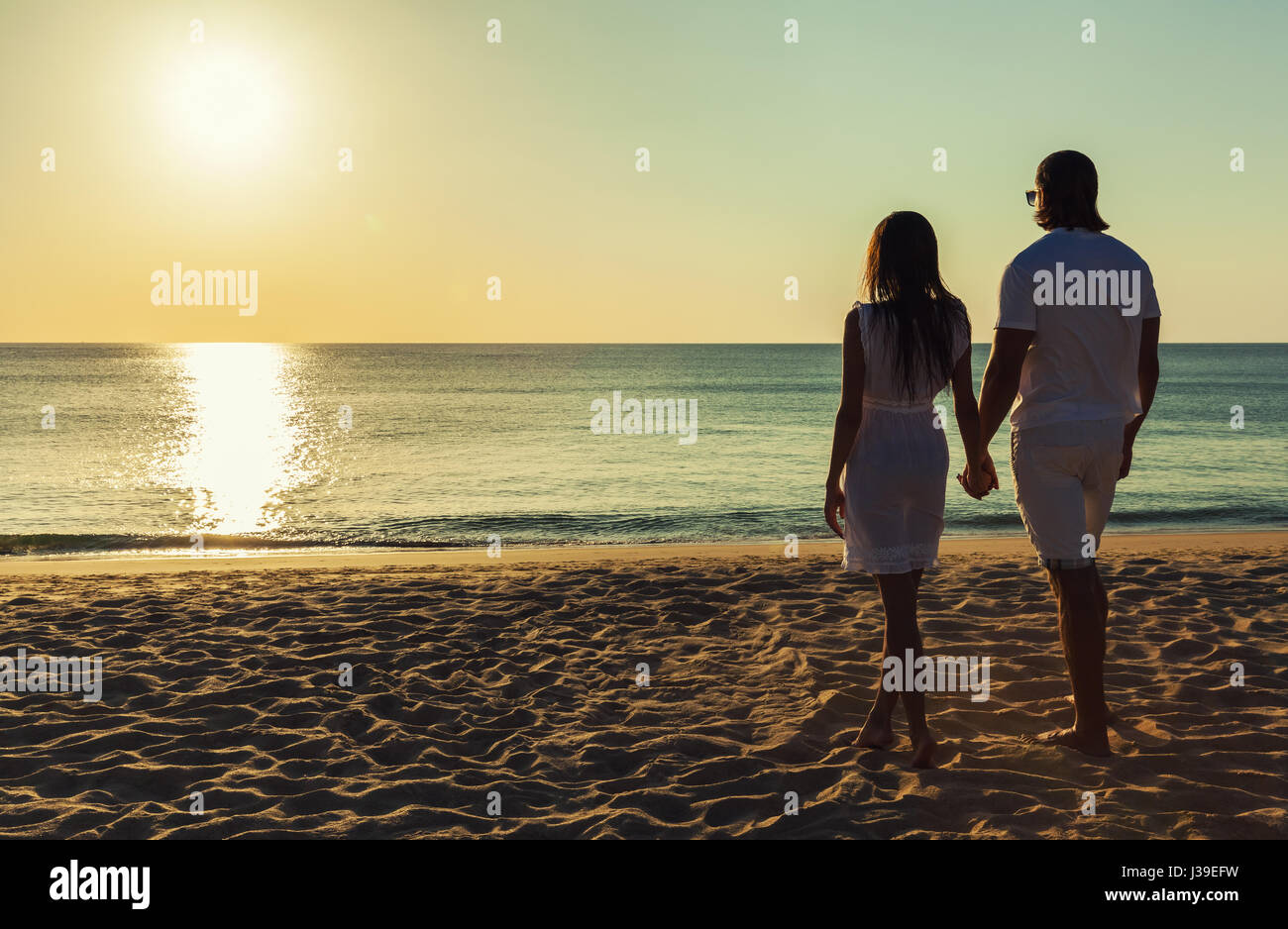 Happy young couple meets sunset on a tropical beach. Lovers in full ...