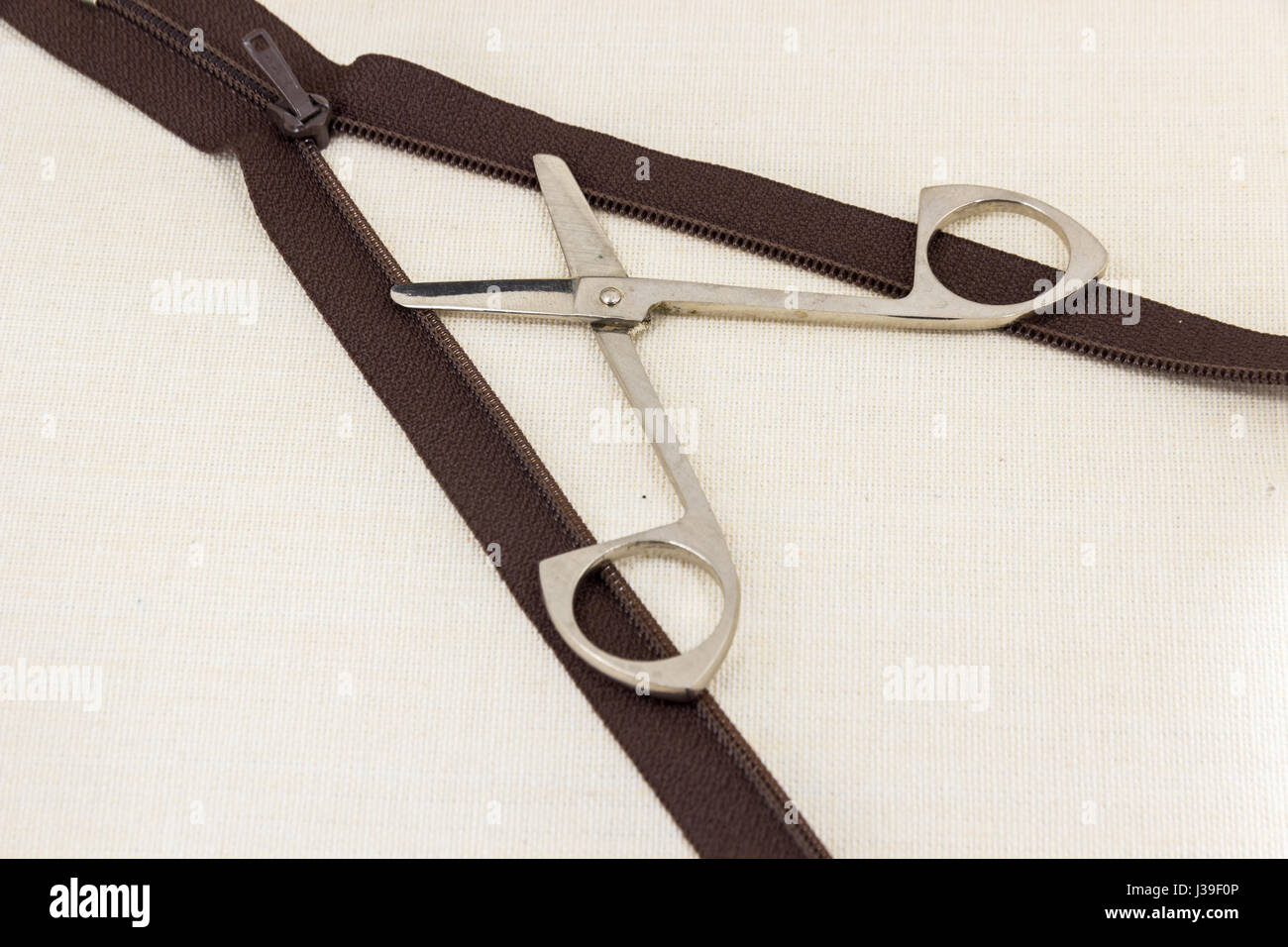 Open zipper and open scissors on a textile background, accessories for ...