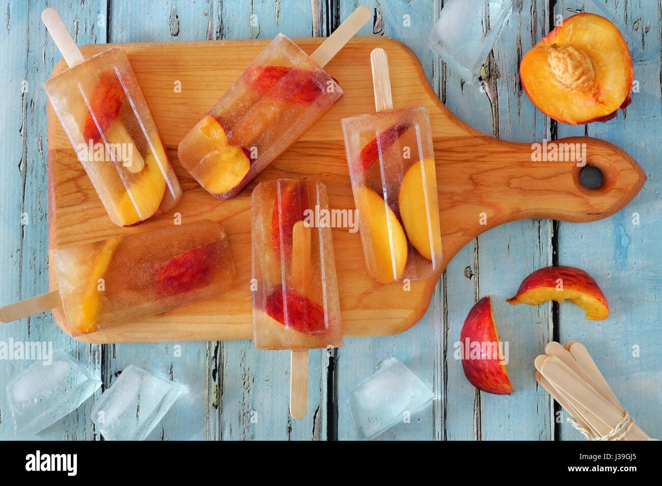 Homemade peach iced tea popsicles, on paddle board against rustic blue ...