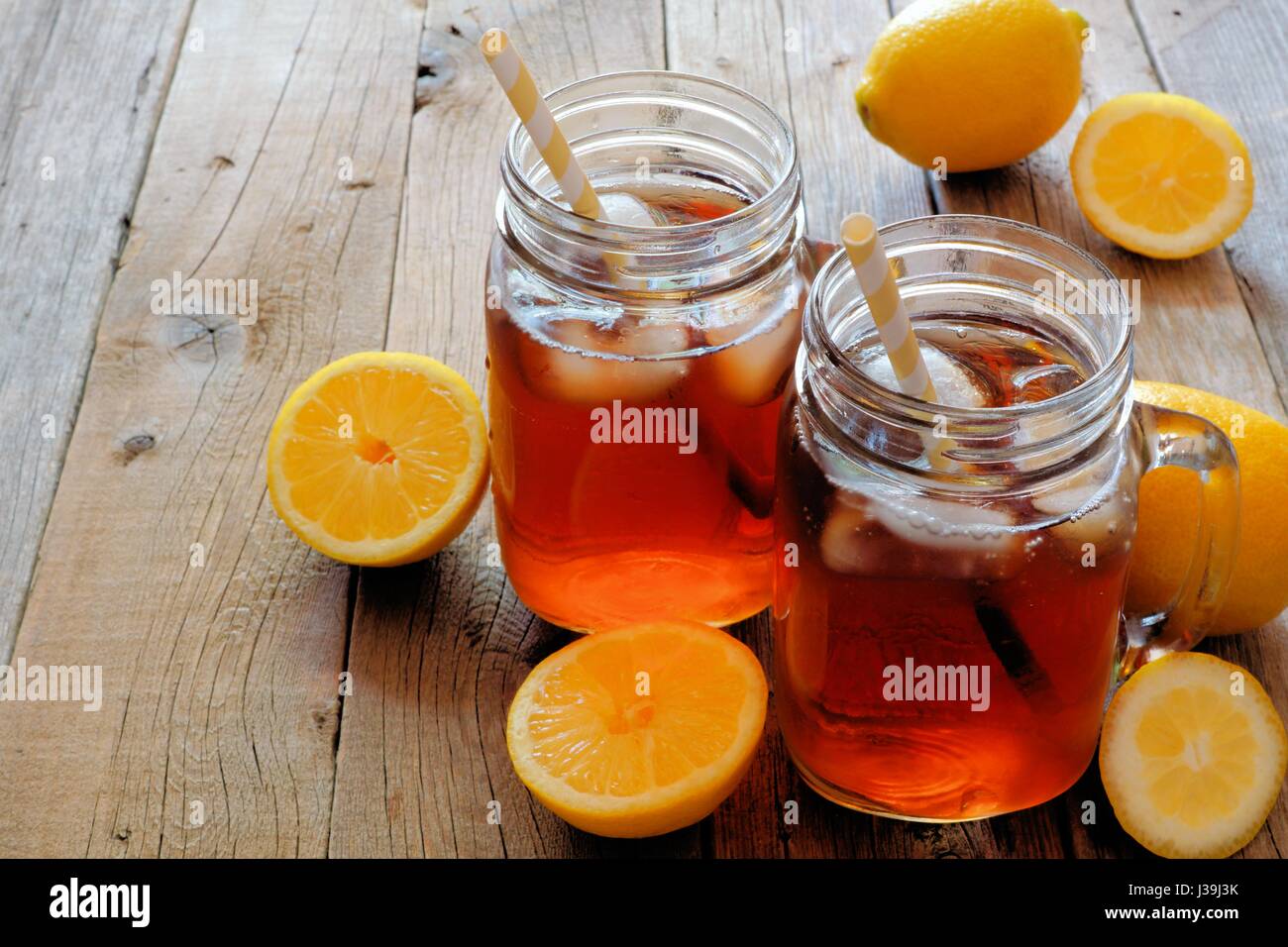 Two mason jar glasses of homemade lemon iced tea on a rustic wooden ...