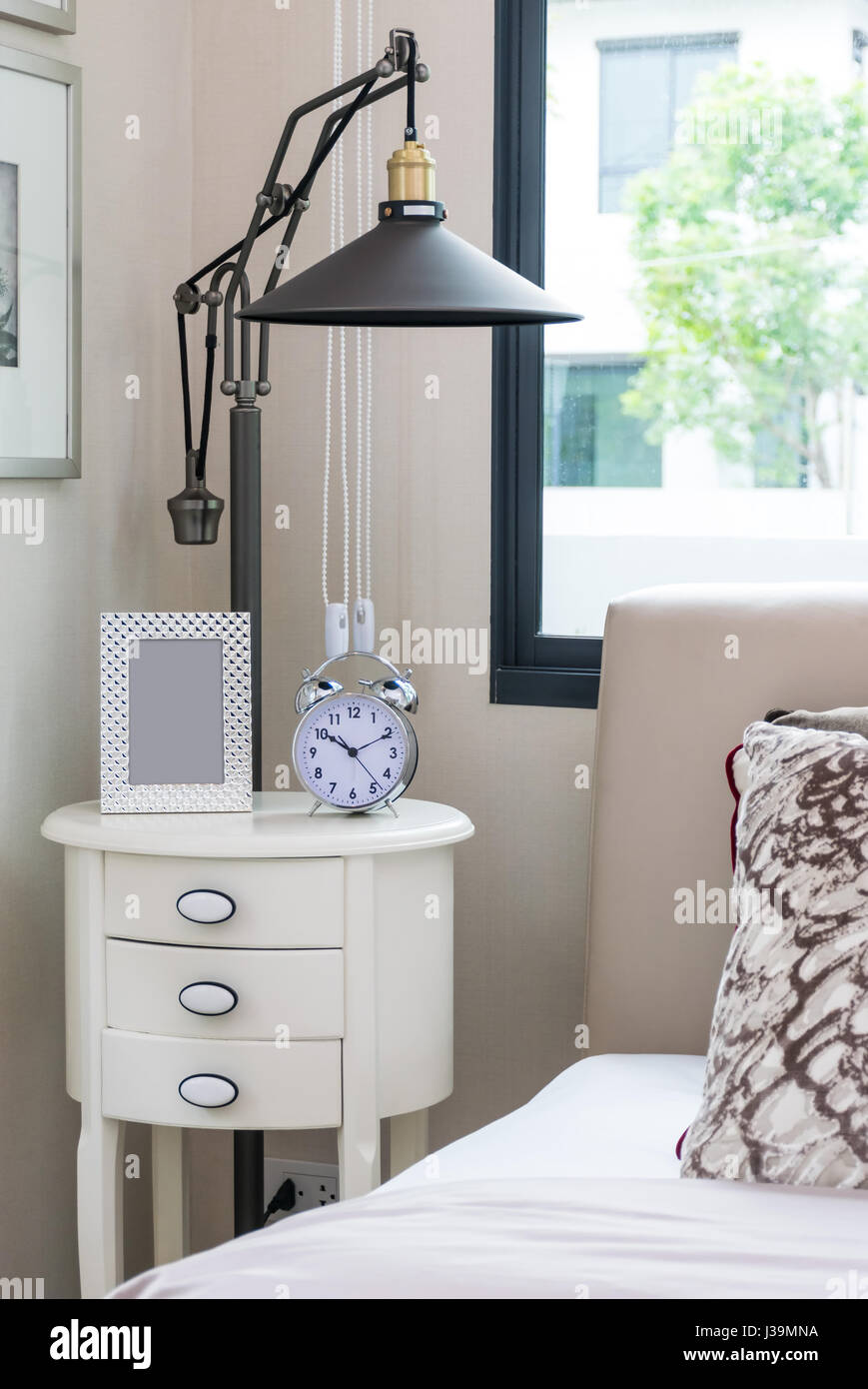 black lamp, picture frame and alarm clock on bedside table Stock Photo ...