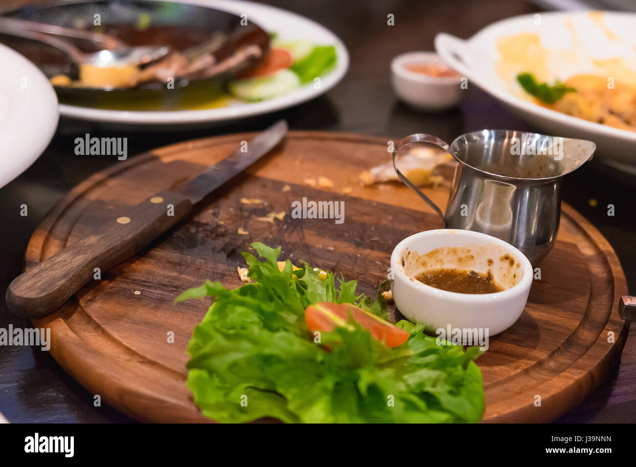 Empty wooden plate after eating pork steak on the wooden table in dark ...