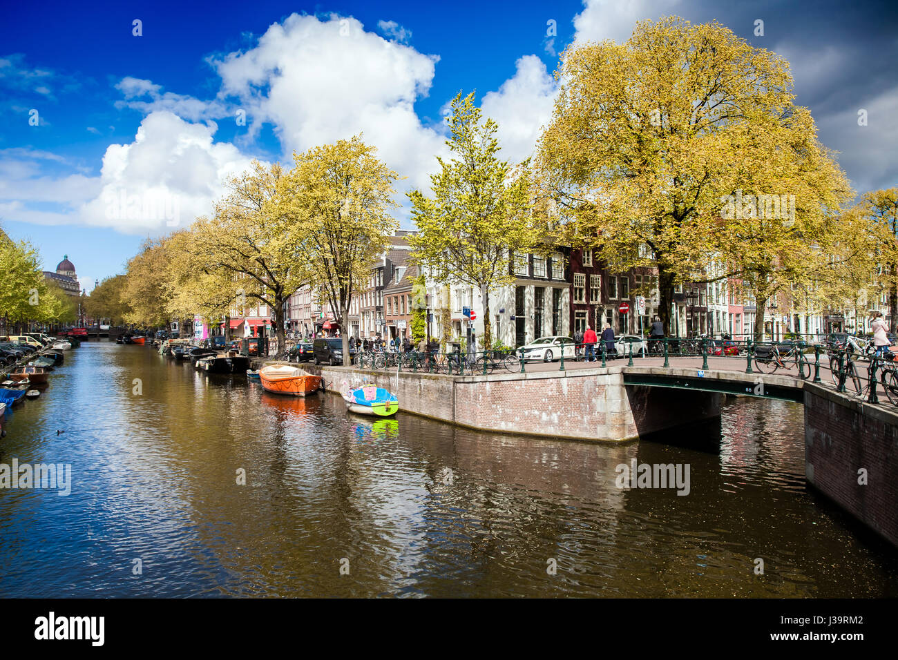 Sunny spring day in Amsterdam. Canal view with boats and bicycles ...