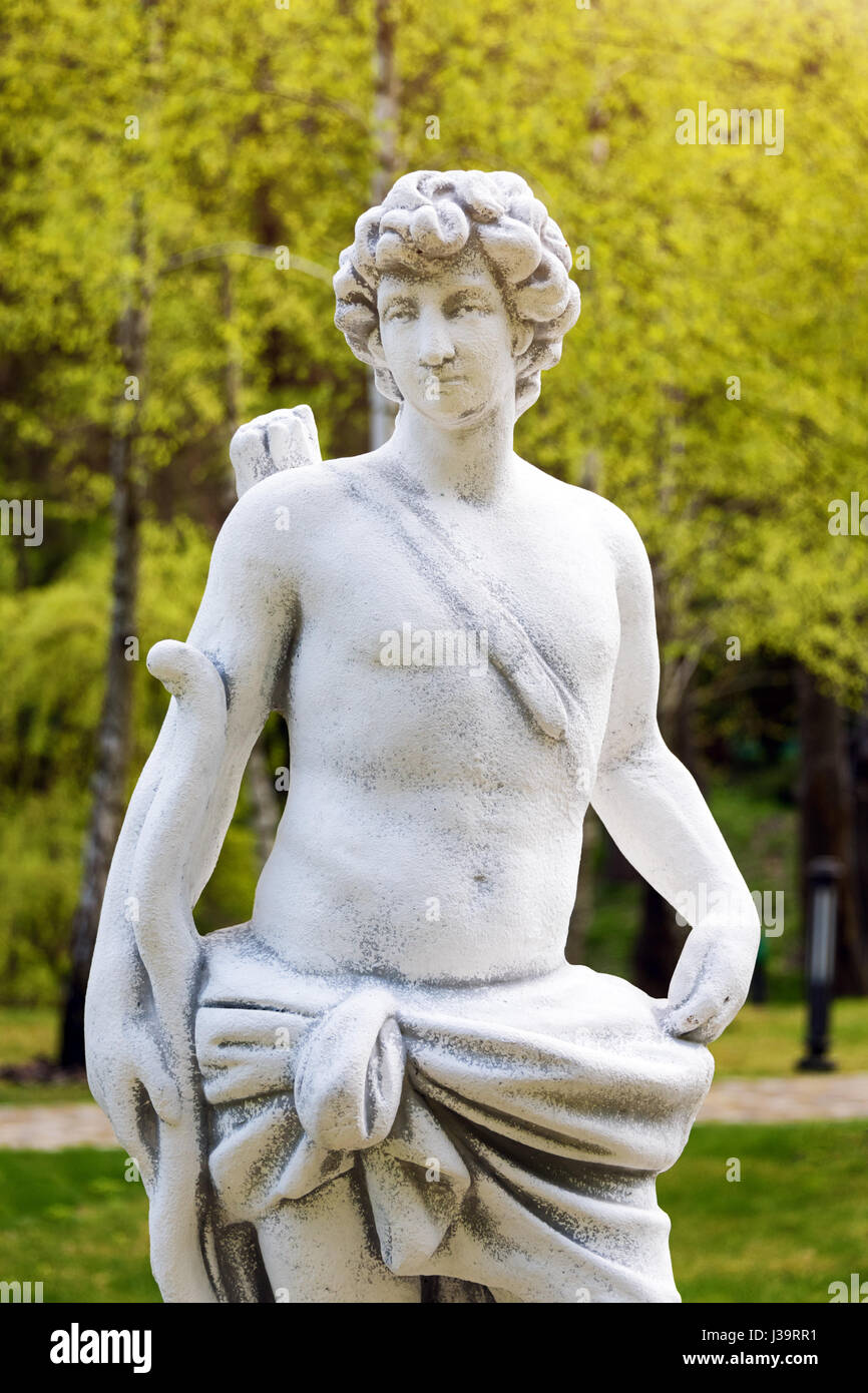 Sculpture in classic style. Statue of a man hunter with bow in the park ...