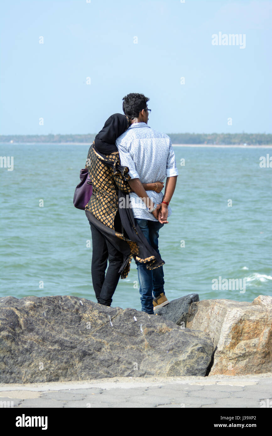 A young Keralan couple embrace and look out to sea at Beypore beach ...