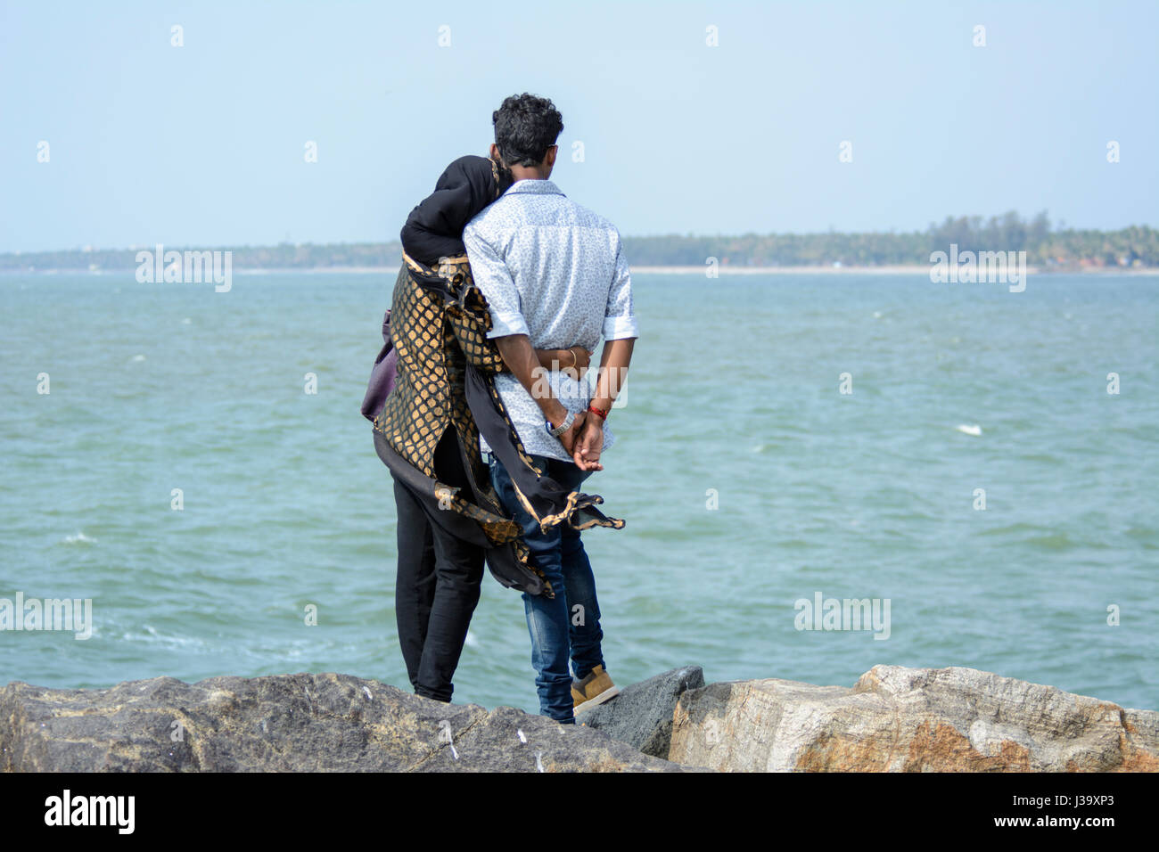 A young Keralan couple embrace and look out to sea at Beypore beach ...