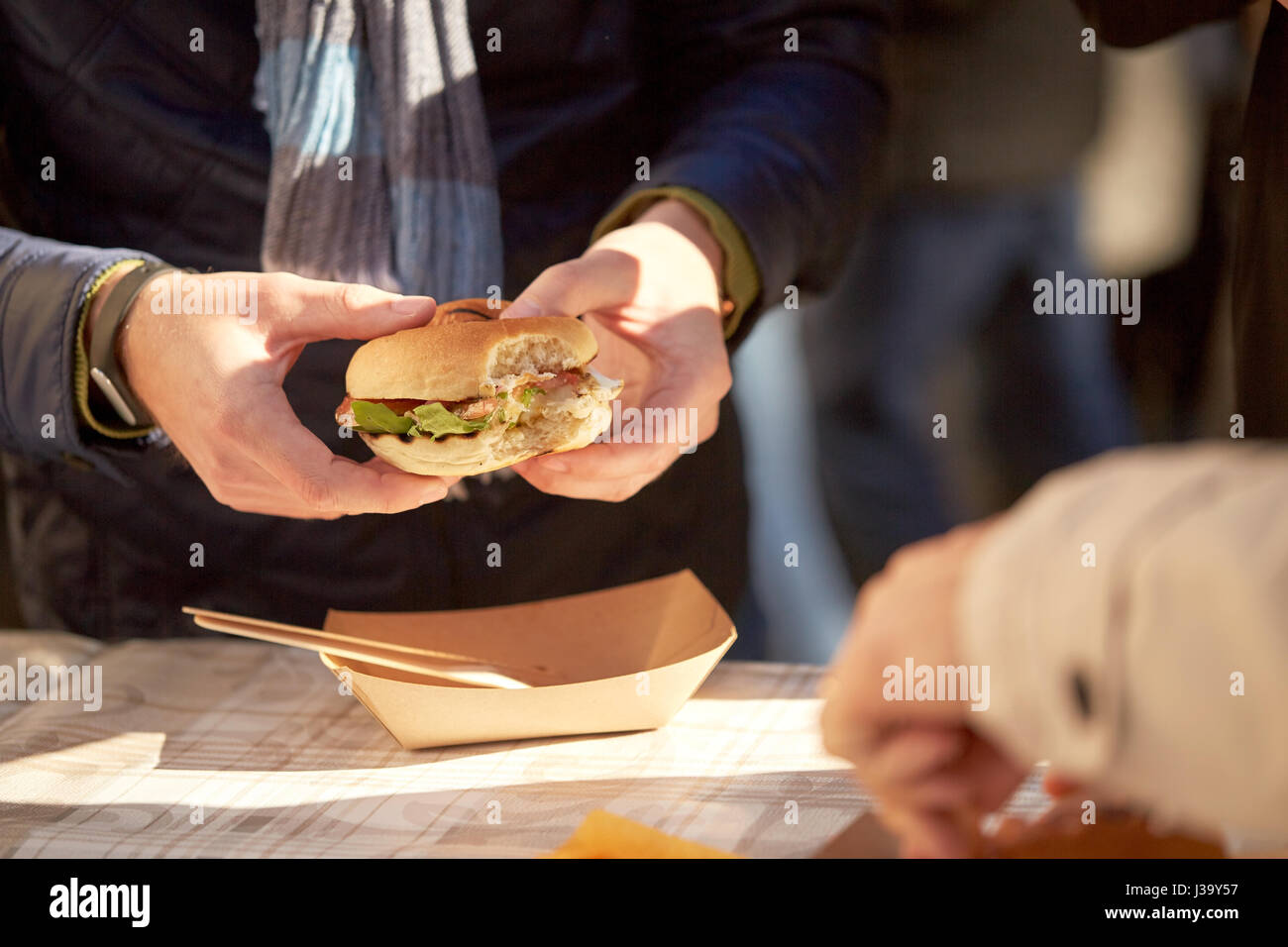hands of man eating hamburger outdoors Stock Photo - Alamy