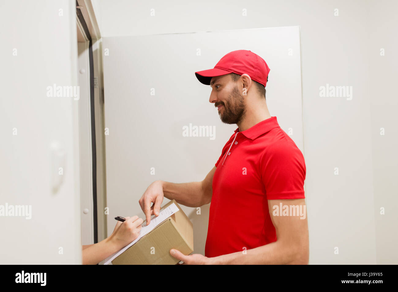 delivery man with box and customer signing form Stock Photo - Alamy