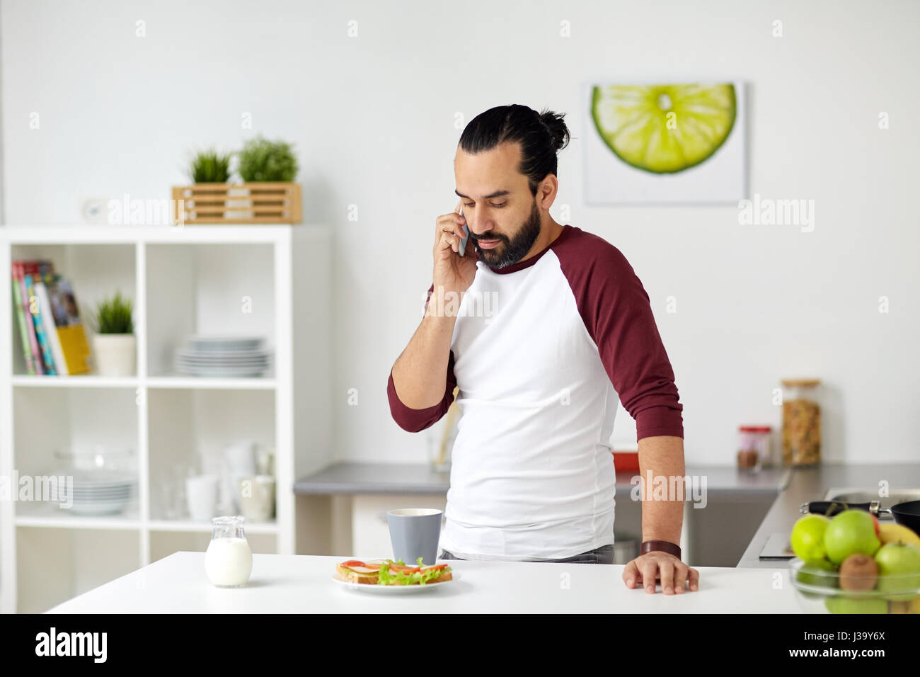 man calling on smartphone and eating at home Stock Photo - Alamy