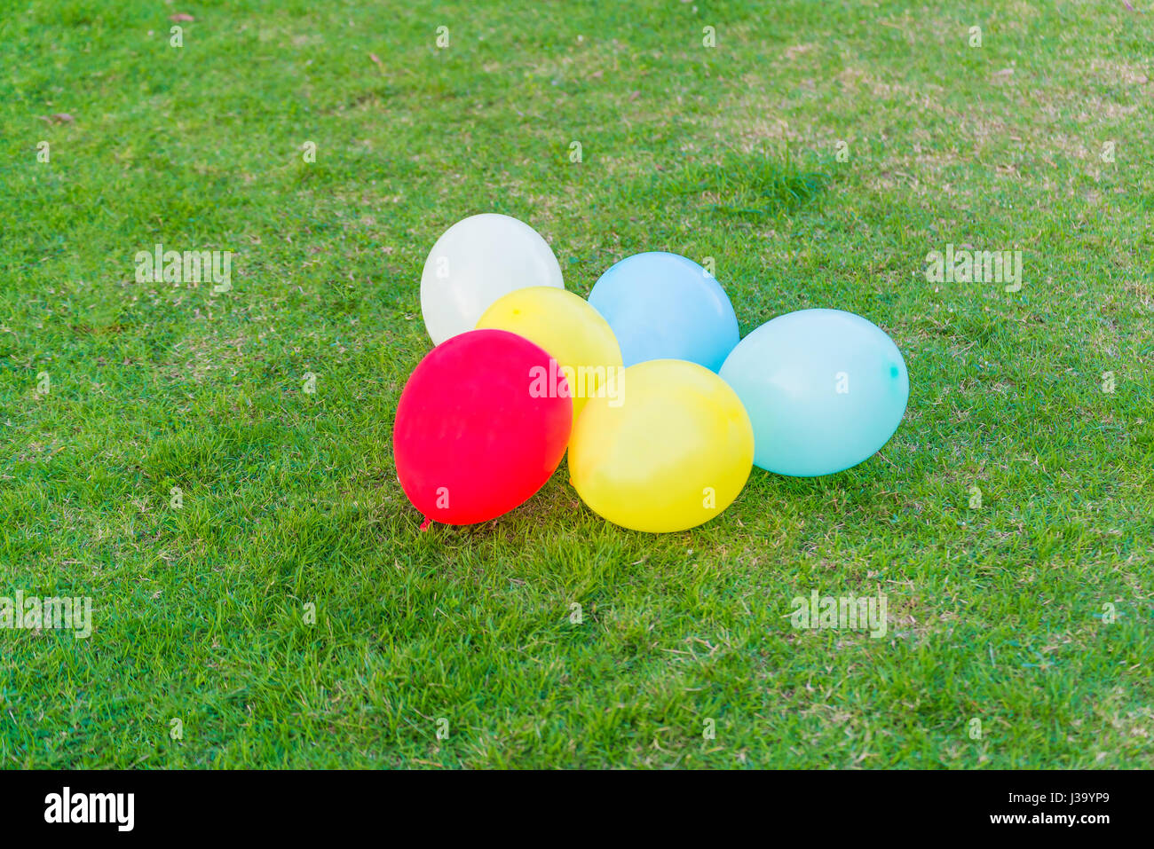 Different colored balloons in the grass field Stock Photo - Alamy