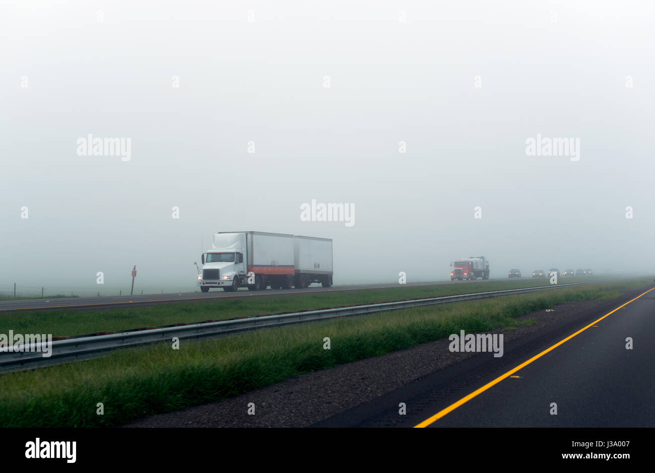 Big rig semi truck with double trailers moves ahead of the column of ...