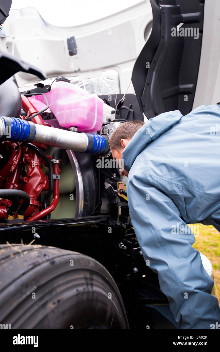 Truck driver of semi truck carefully check the running engine with a ...