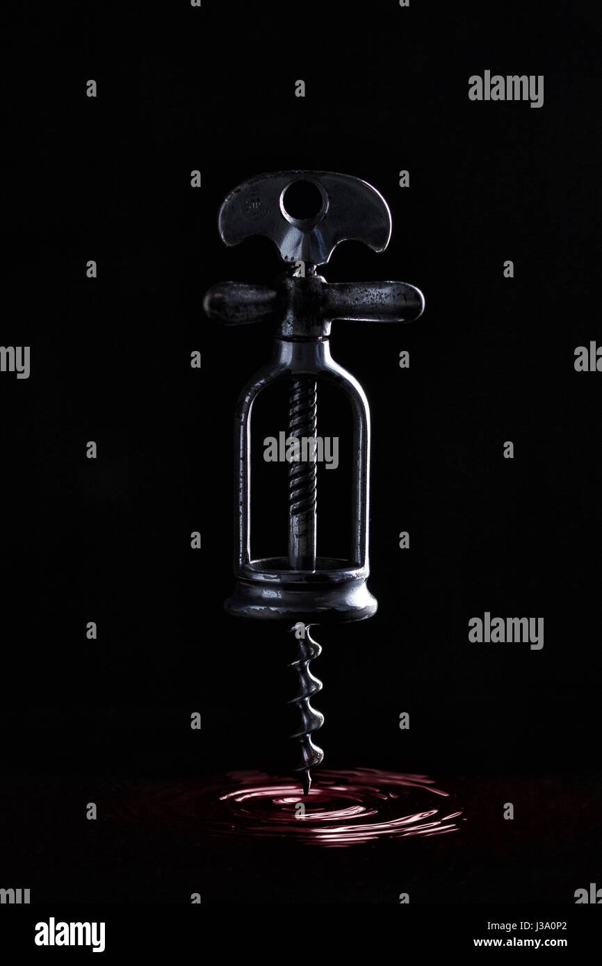 Antique corkscrew hanging in the air on a black background. An ancient ...