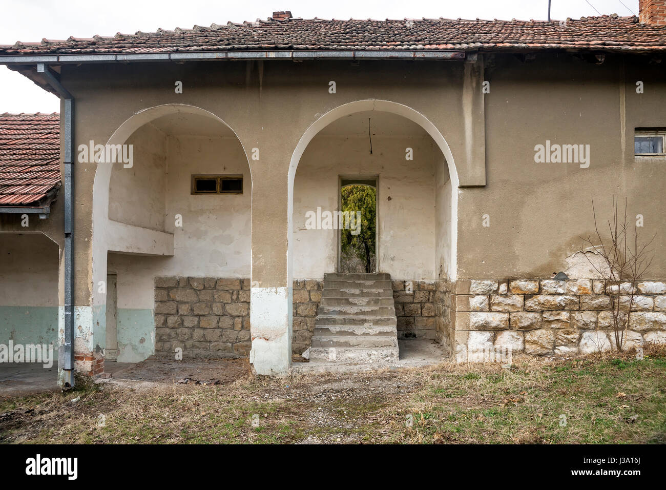Old abandoned building with arc pillars and a porch in the village ...
