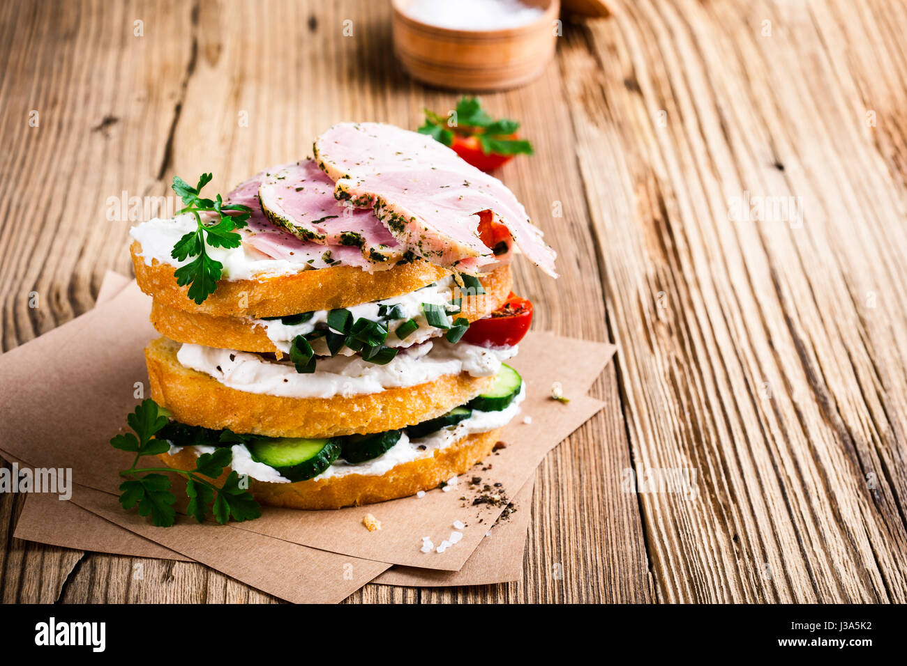 Stack of sandwiches with cream cheese, ham,cucumber, tomato and green ...