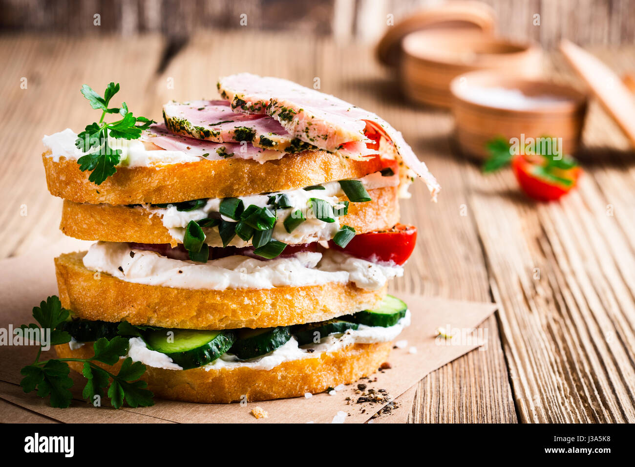Stack of sandwiches with cream cheese, ham,cucumber, tomato and green ...