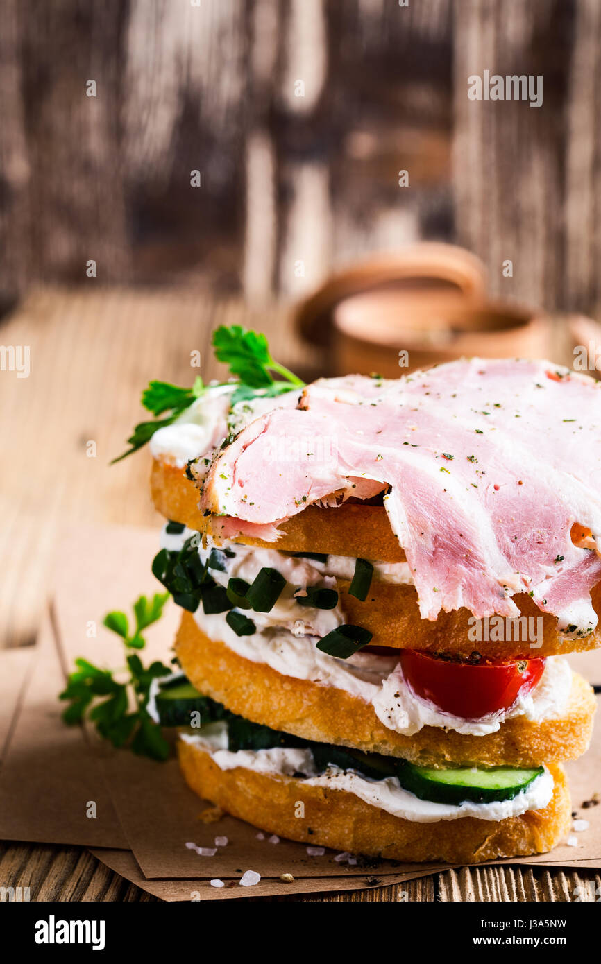 Stack of sandwiches with cream cheese, ham,cucumber, tomato and green ...
