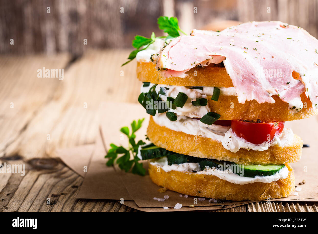Stack of sandwiches with cream cheese, ham,cucumber, tomato and green ...