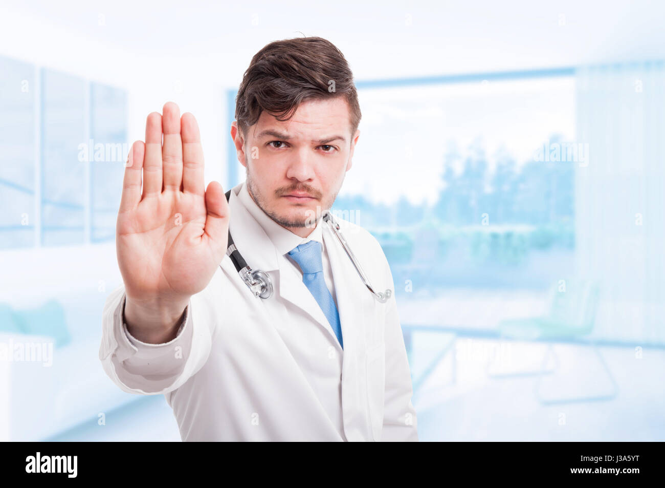 Angry male doctor in medical coat with repelling gesture with ...