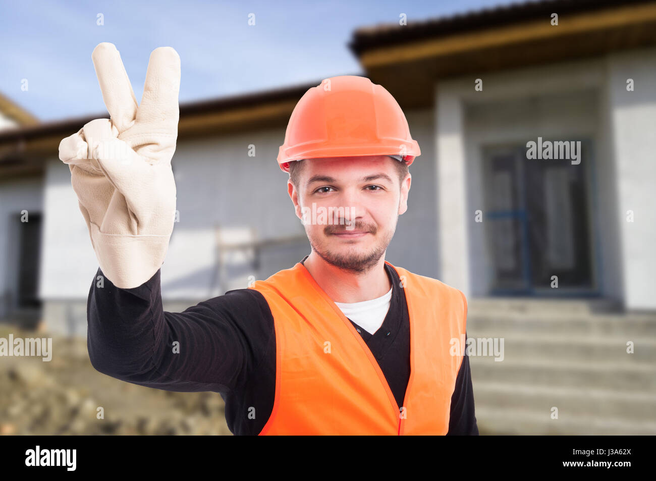 Happy man with helmet showing two fingers as victory sign outside at ...