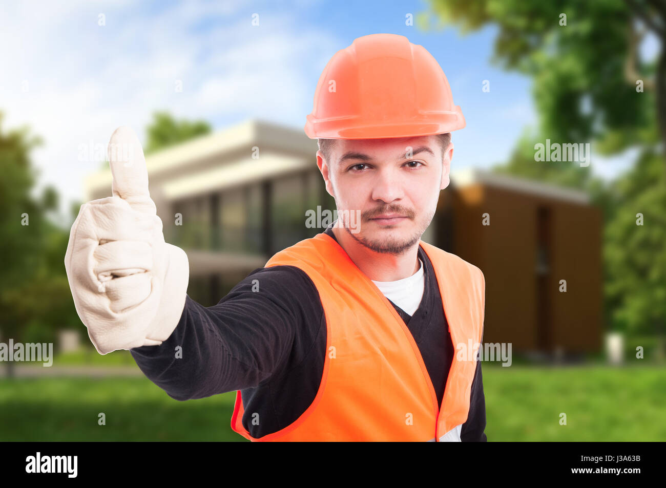 Portrait of handsome engineer thumbs up outside in front of the house ...