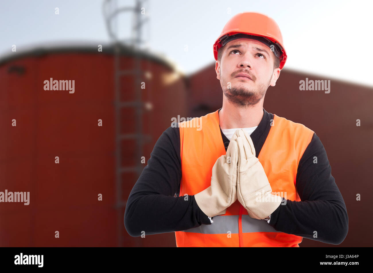 Young worried builder praying for a miracle on construction site with ...