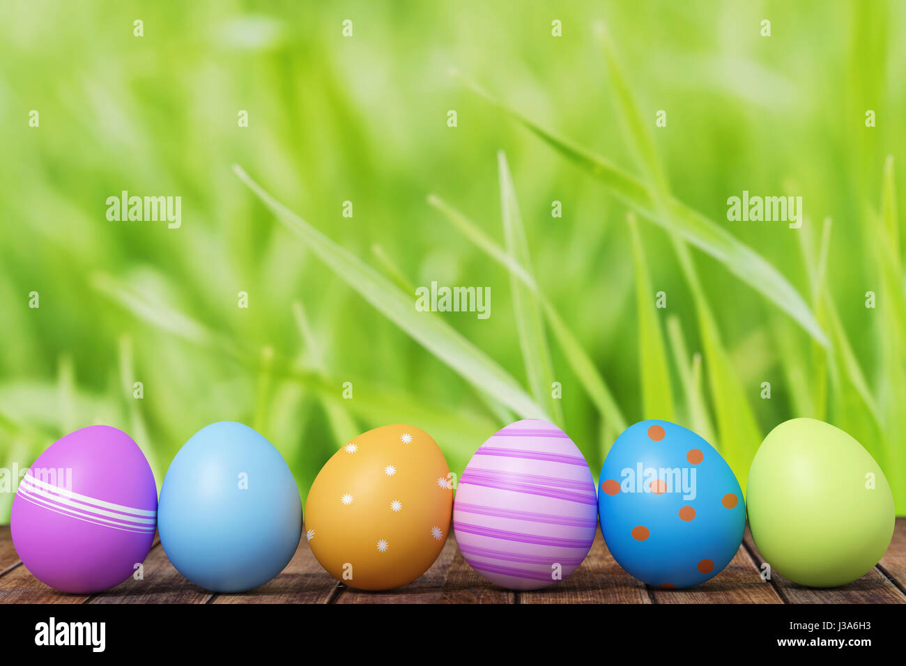 Row of Easter eggs on grass with a wood background Stock Photo - Alamy