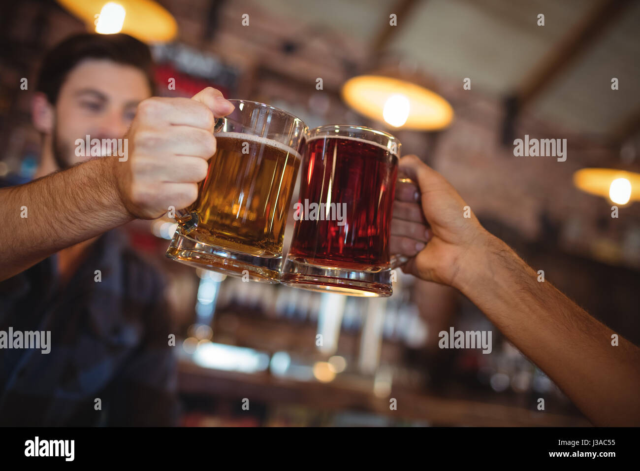 Two young men toasting their beer mugs in pub Stock Photo - Alamy