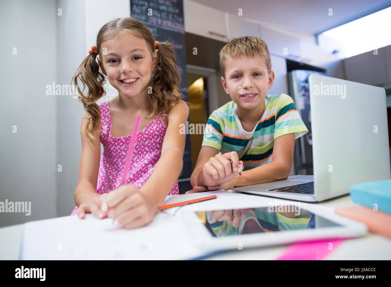 Portrait of siblings doing their homework in kitchen at home Stock ...