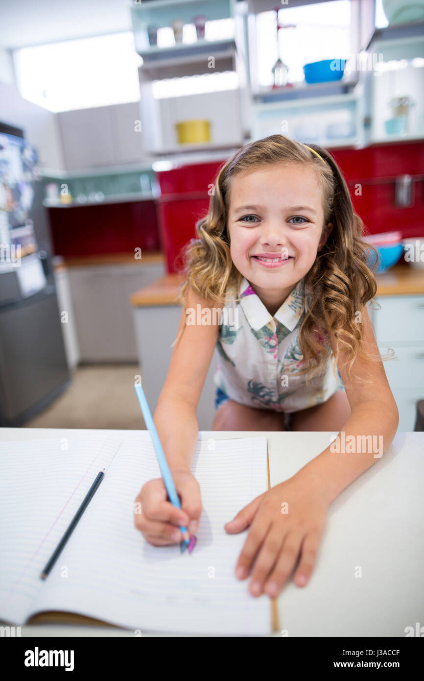 Portrait of smiling girl doing homework in kitchen at home Stock Photo ...
