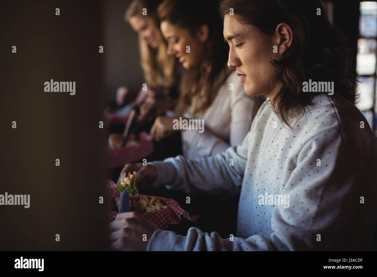 Friends having burger together at restaurant Stock Photo - Alamy