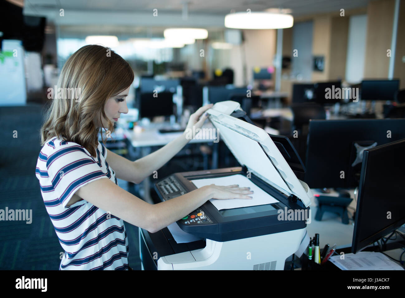 Side view of businesswoman using copy machine in office Stock Photo - Alamy