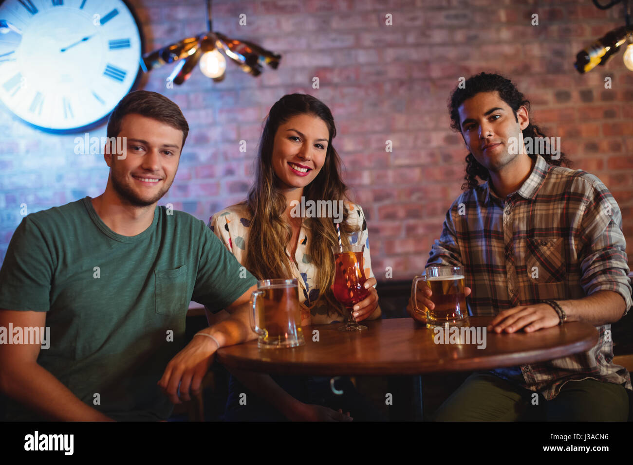 Portrait of young friends having drinks in pub Stock Photo - Alamy
