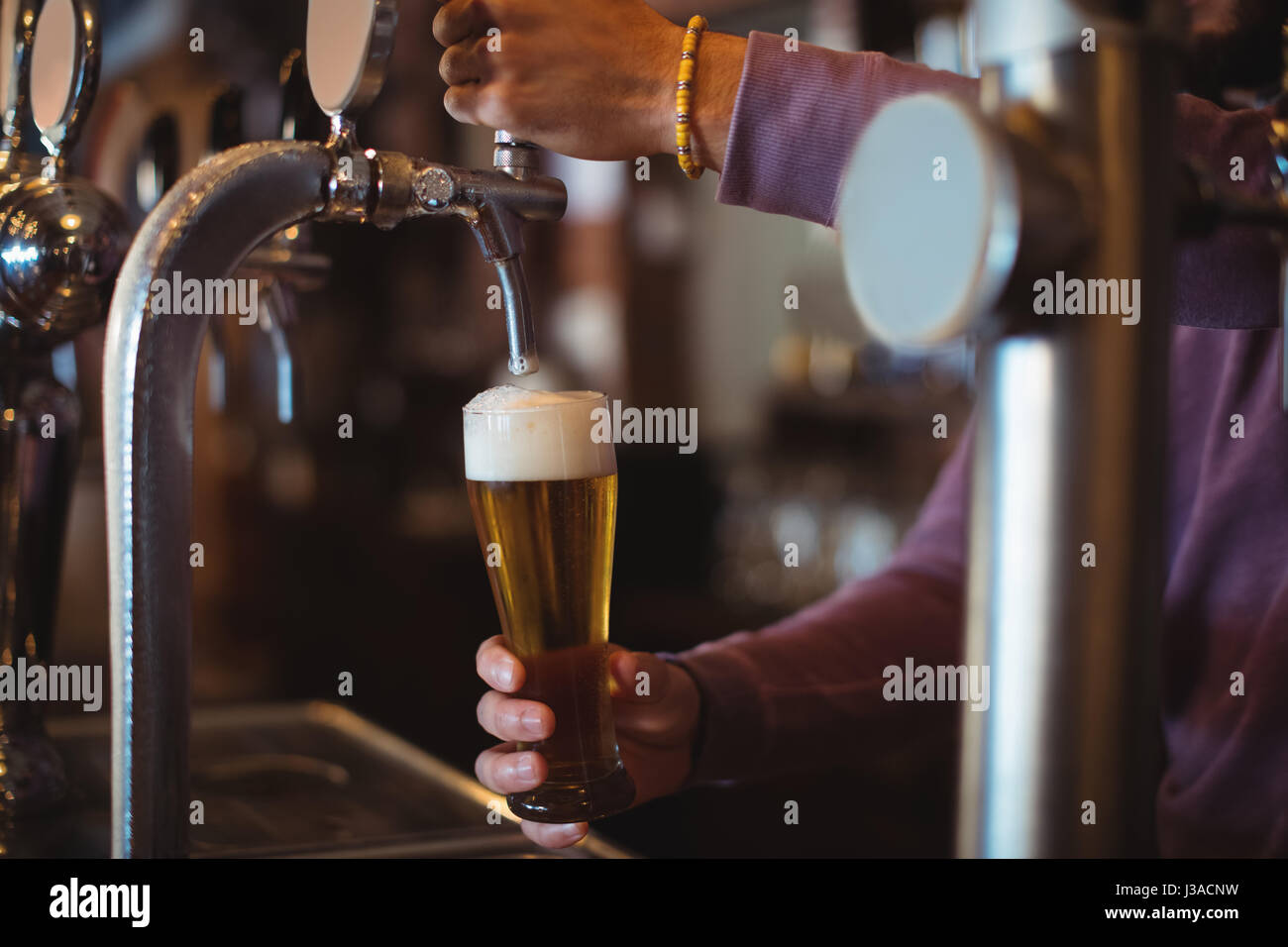 Close-up of bar tender filling beer from beer pump at bar counter Stock ...