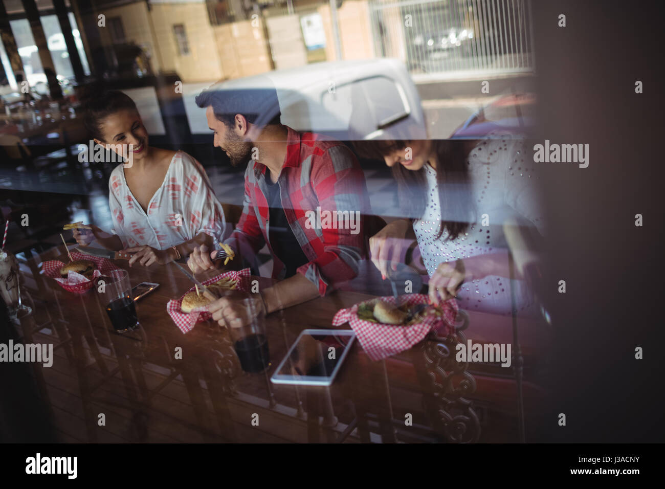 Friends having burger together at restaurant Stock Photo - Alamy