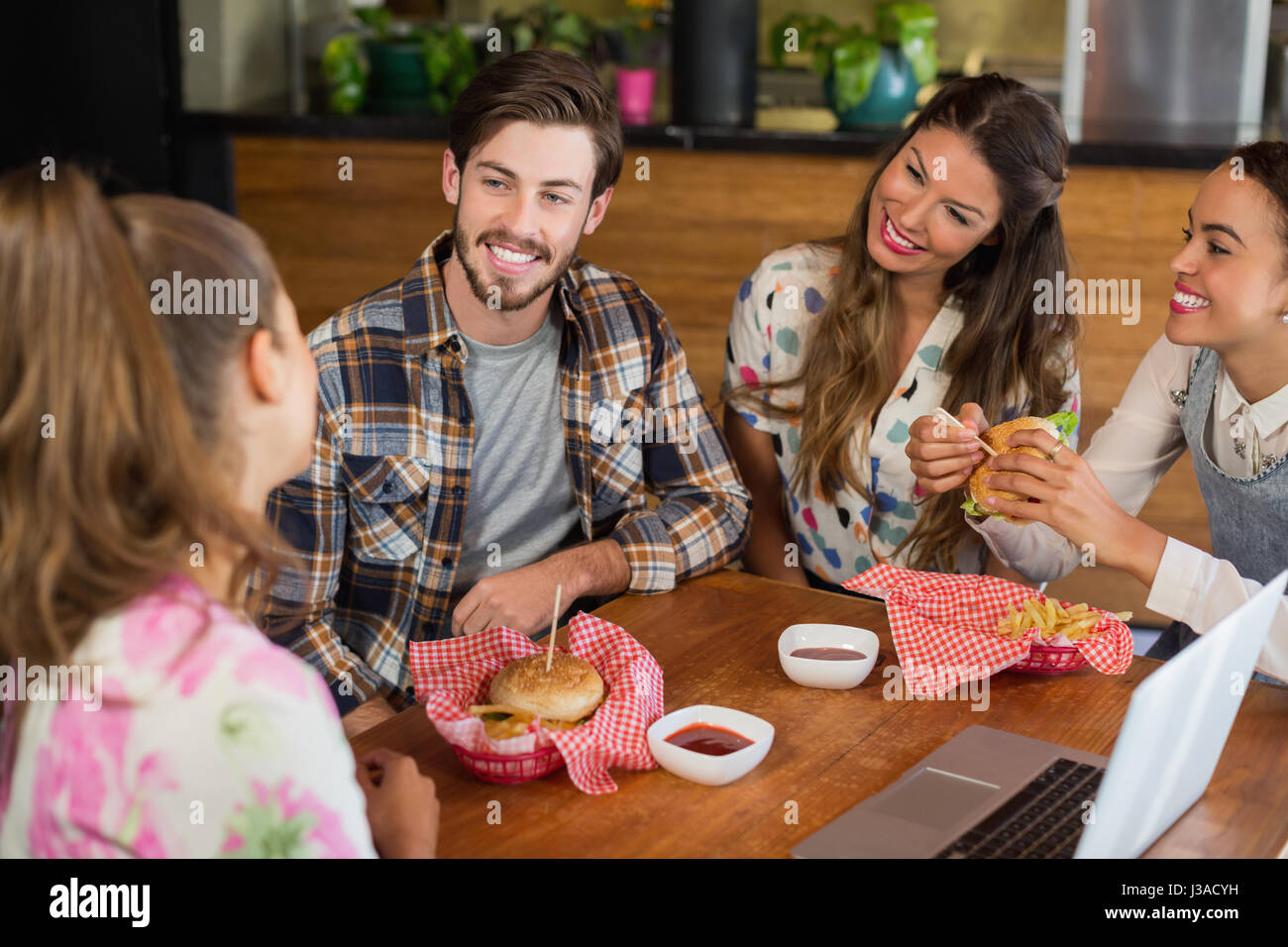 Cheerful friends having burger in restaurant Stock Photo - Alamy