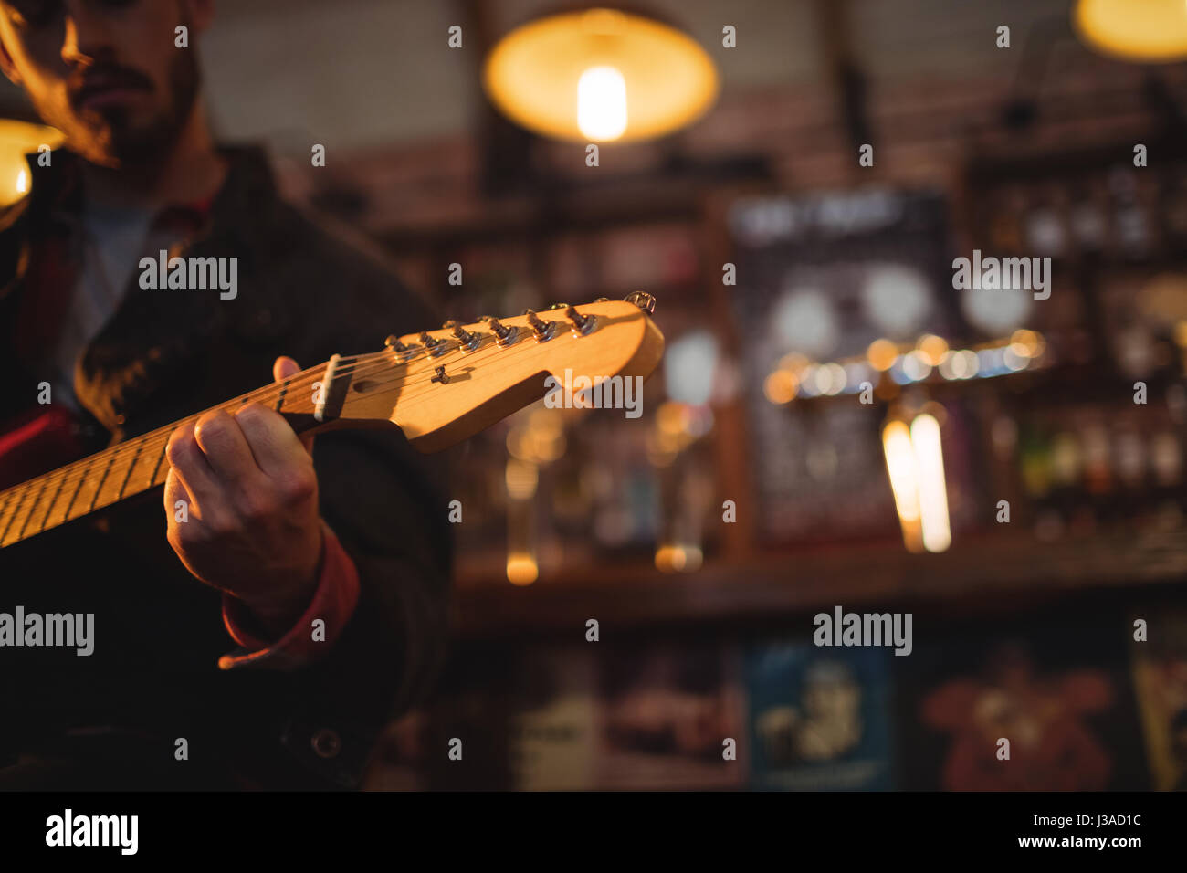 Young man playing guitar in pub Stock Photo - Alamy