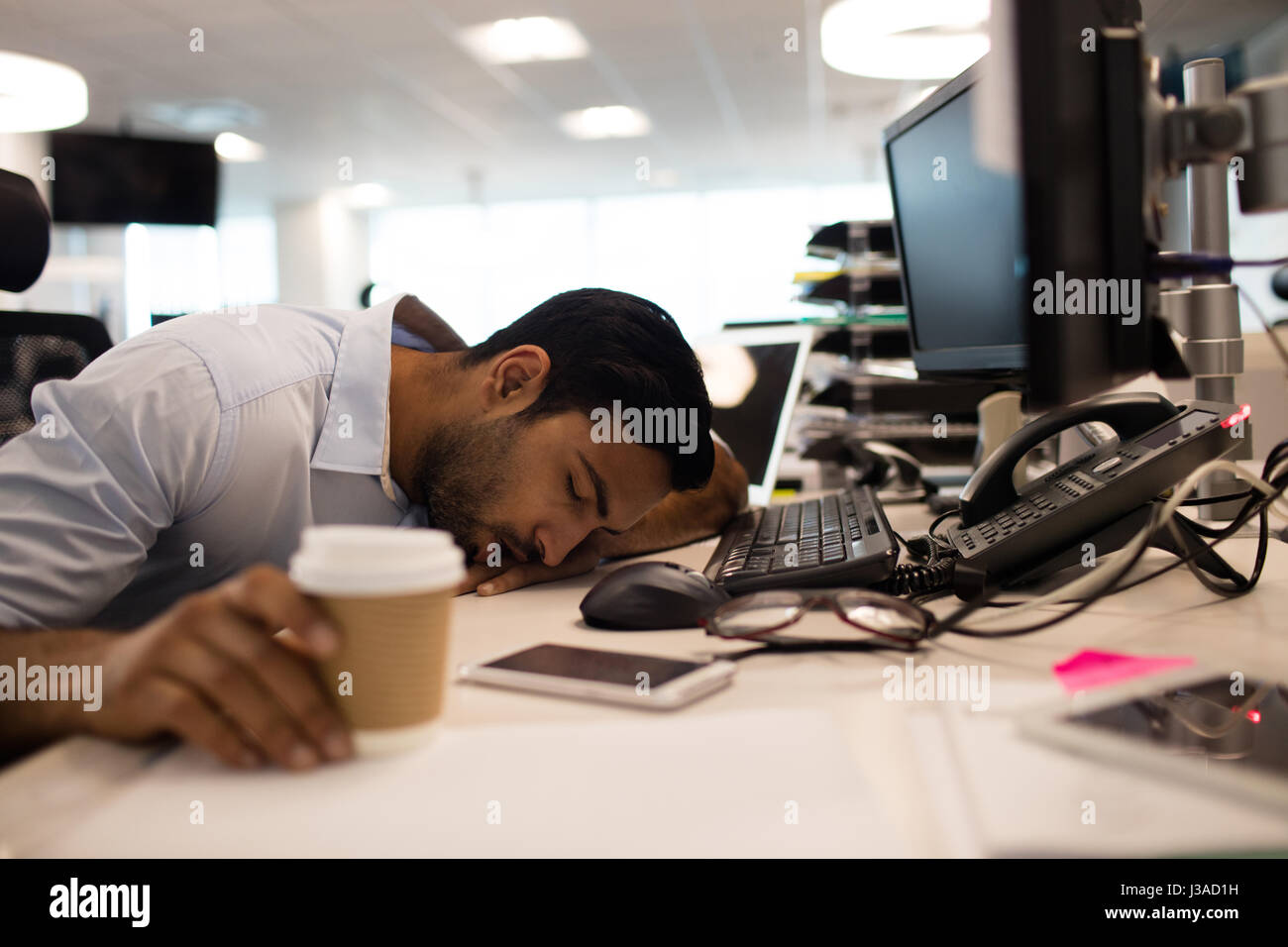 Tired businessman sleeping by desktop computers on desk at office Stock ...
