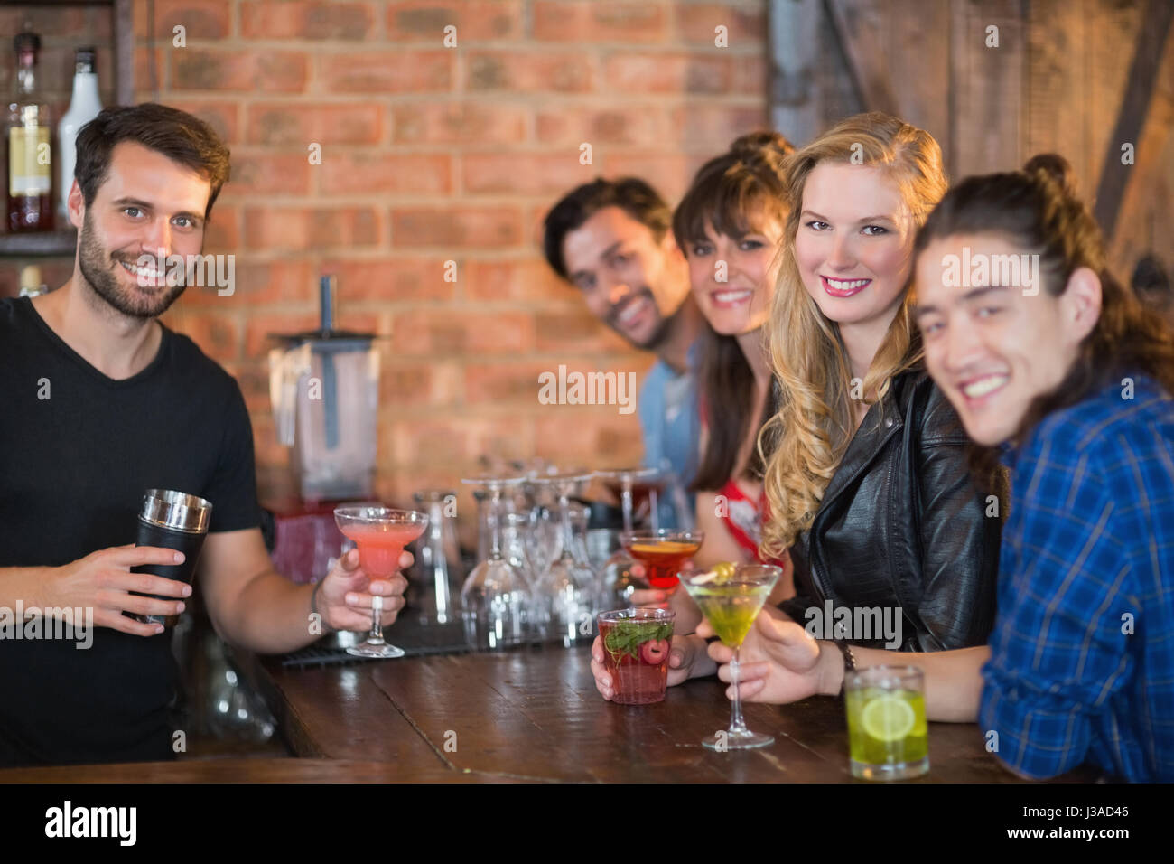 Portrait of bartender serving drinks to happy customers in bar Stock ...