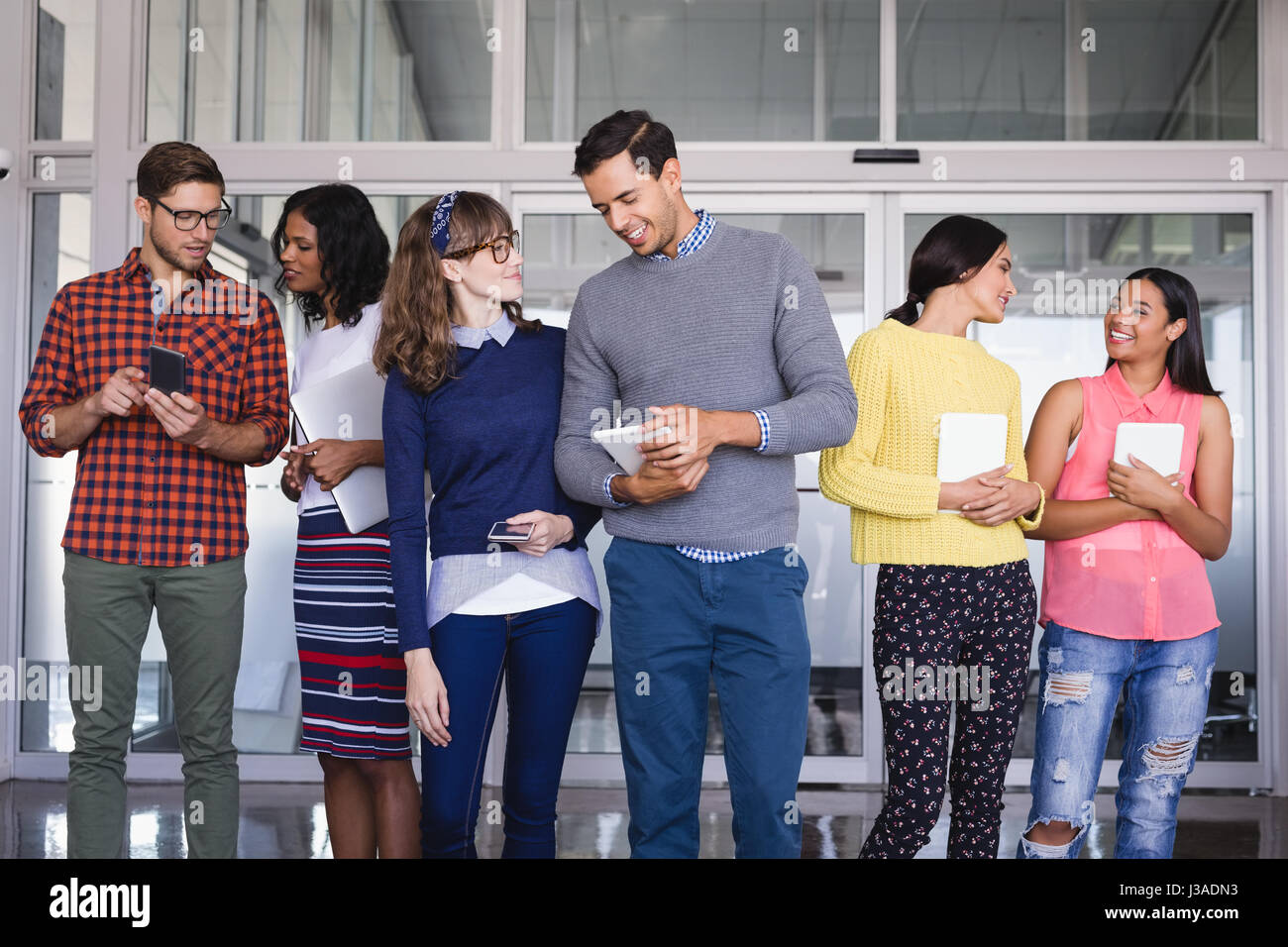 Happy business people with tablet computers standing in corridor Stock ...