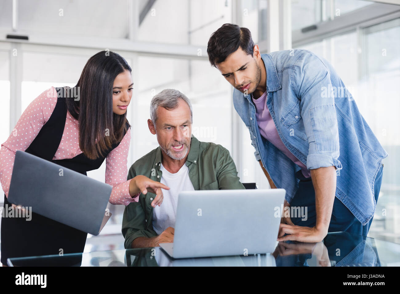 Business people discussing over laptops at desk in office Stock Photo ...