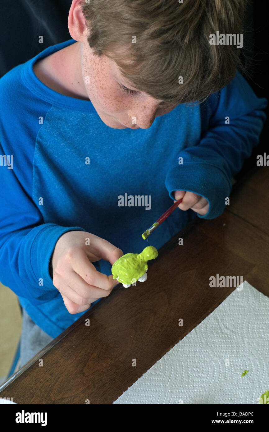 Boy painting a clay turtle Stock Photo - Alamy